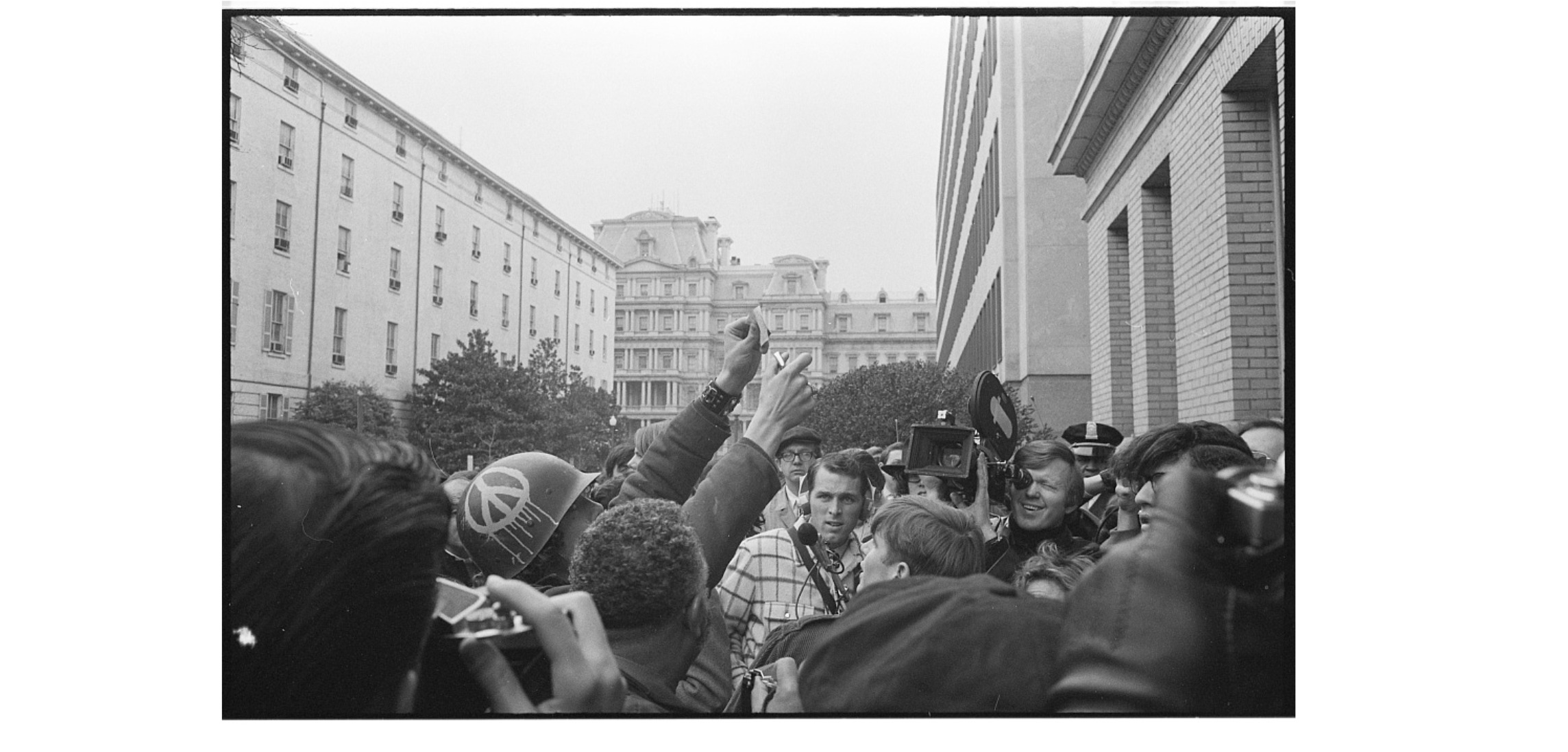 Young man wearing helmet with peace sign, burns his draft card at an ...